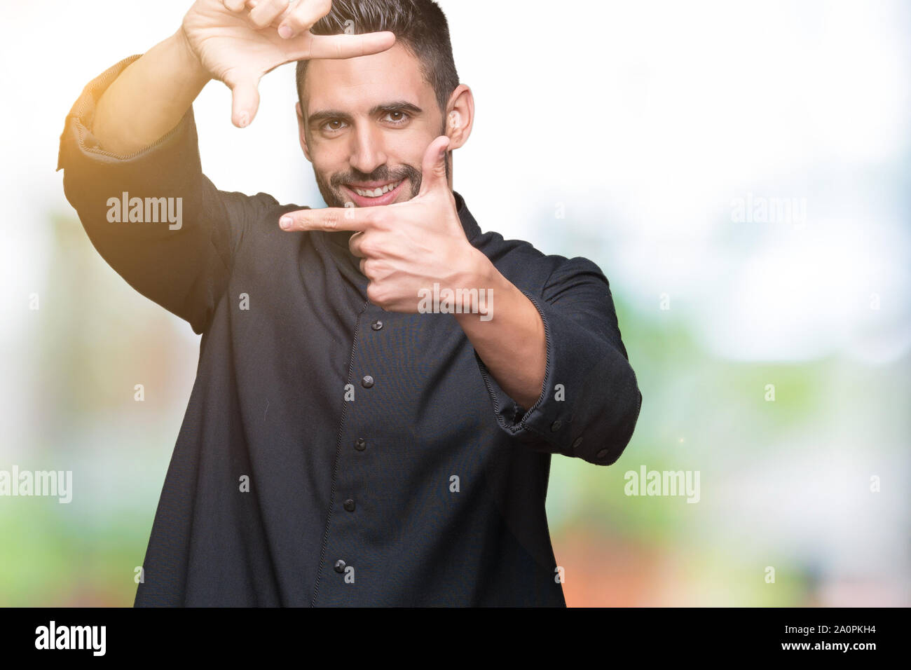 Young Christian priest over isolated background smiling making frame ...