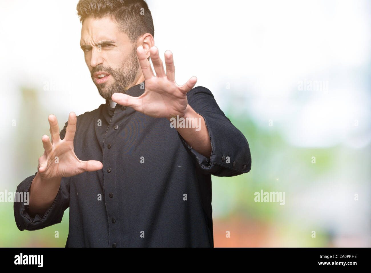 Young Christian priest over isolated background afraid and terrified ...