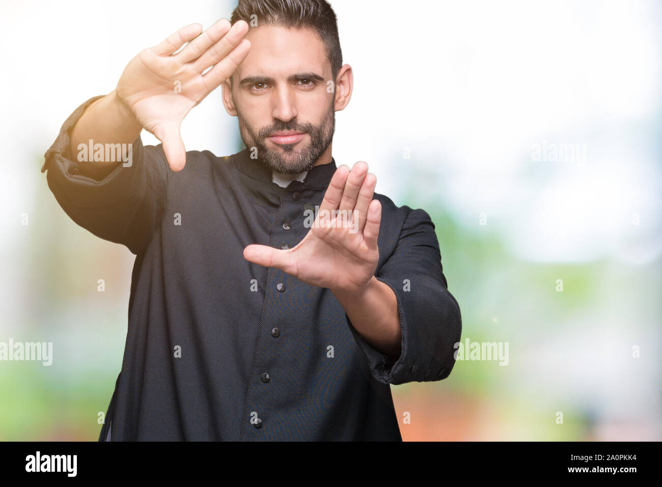 Young Christian priest over isolated background Smiling doing frame ...