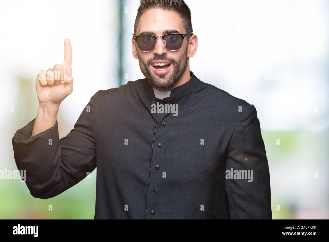 Young Christian priest wearing sunglasses over isolated background ...