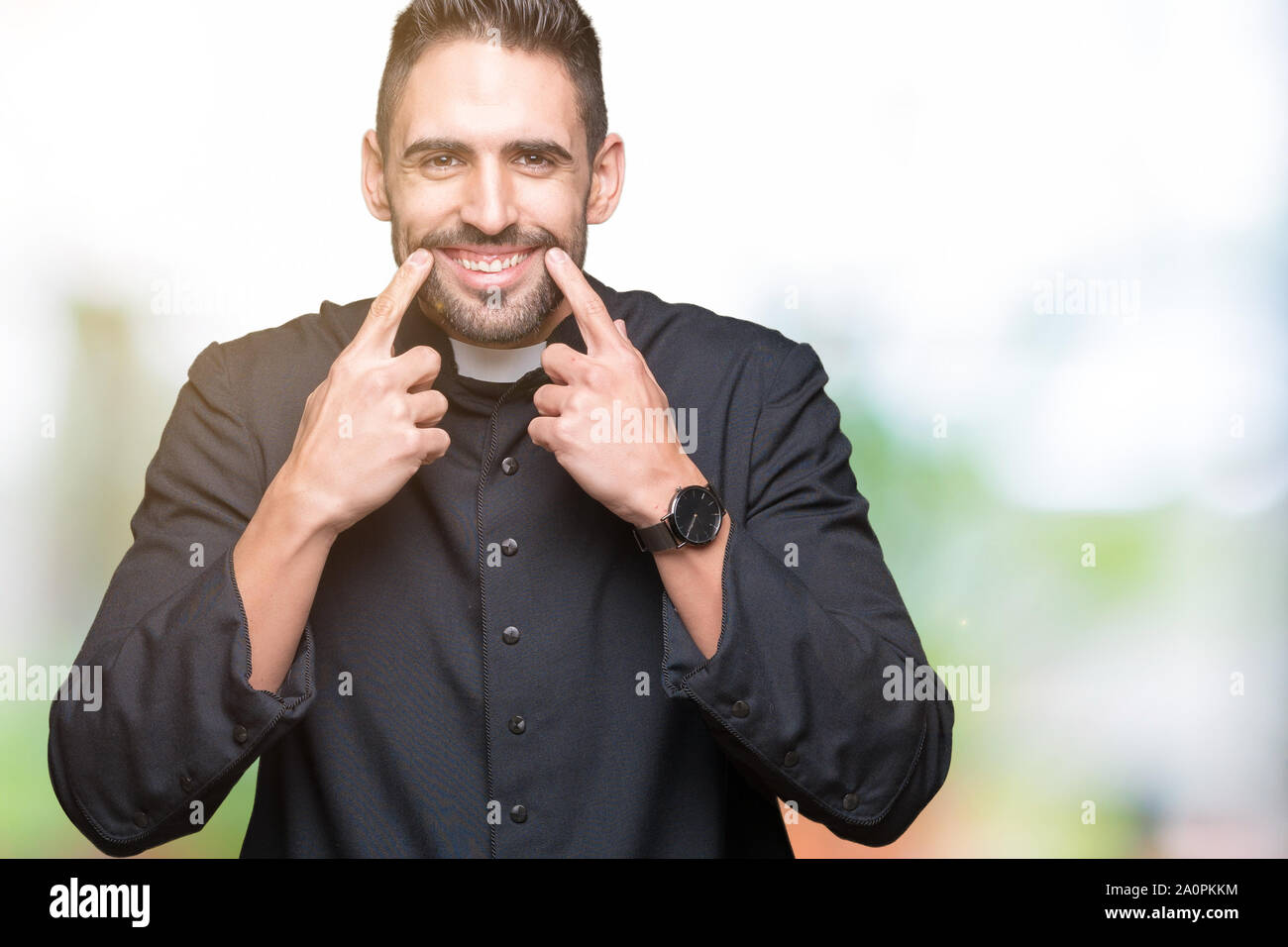 Young Christian priest over isolated background Smiling with open mouth ...