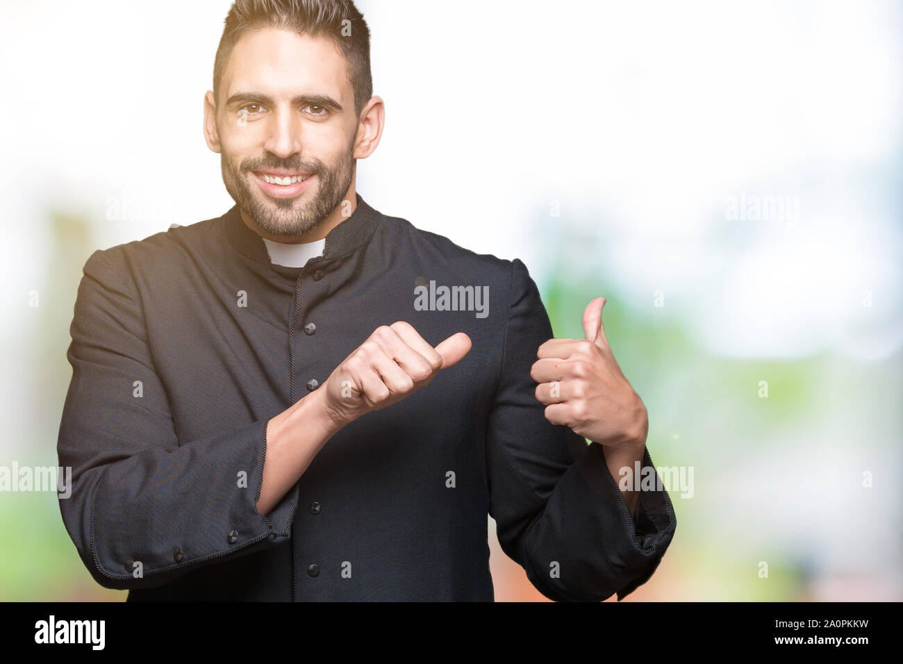 Young Christian priest over isolated background Pointing to the back ...