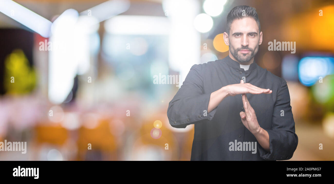 Young Christian priest over isolated background Doing time out gesture ...