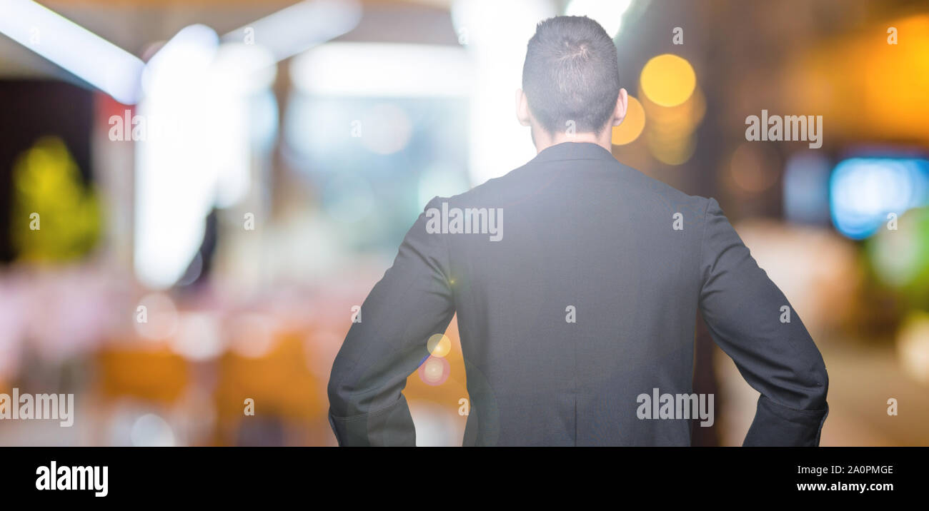 Young Christian priest over isolated background standing backwards ...