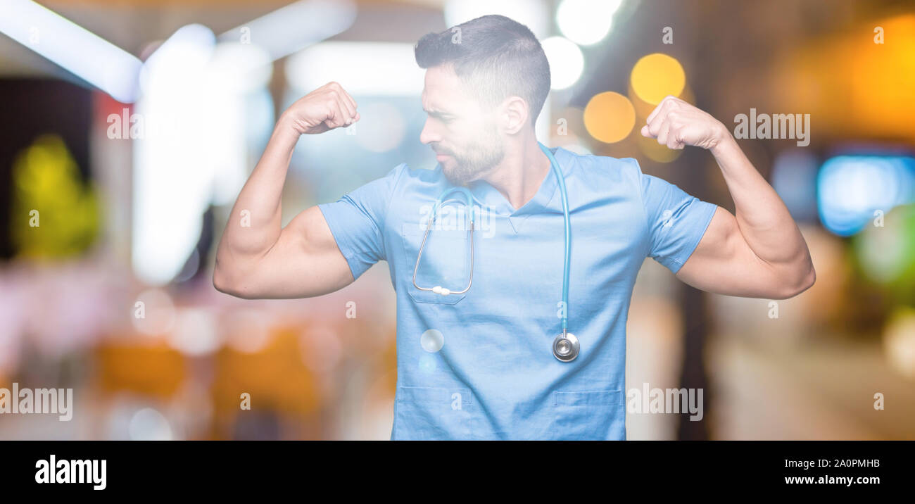Handsome young doctor surgeon man over isolated background showing arms ...