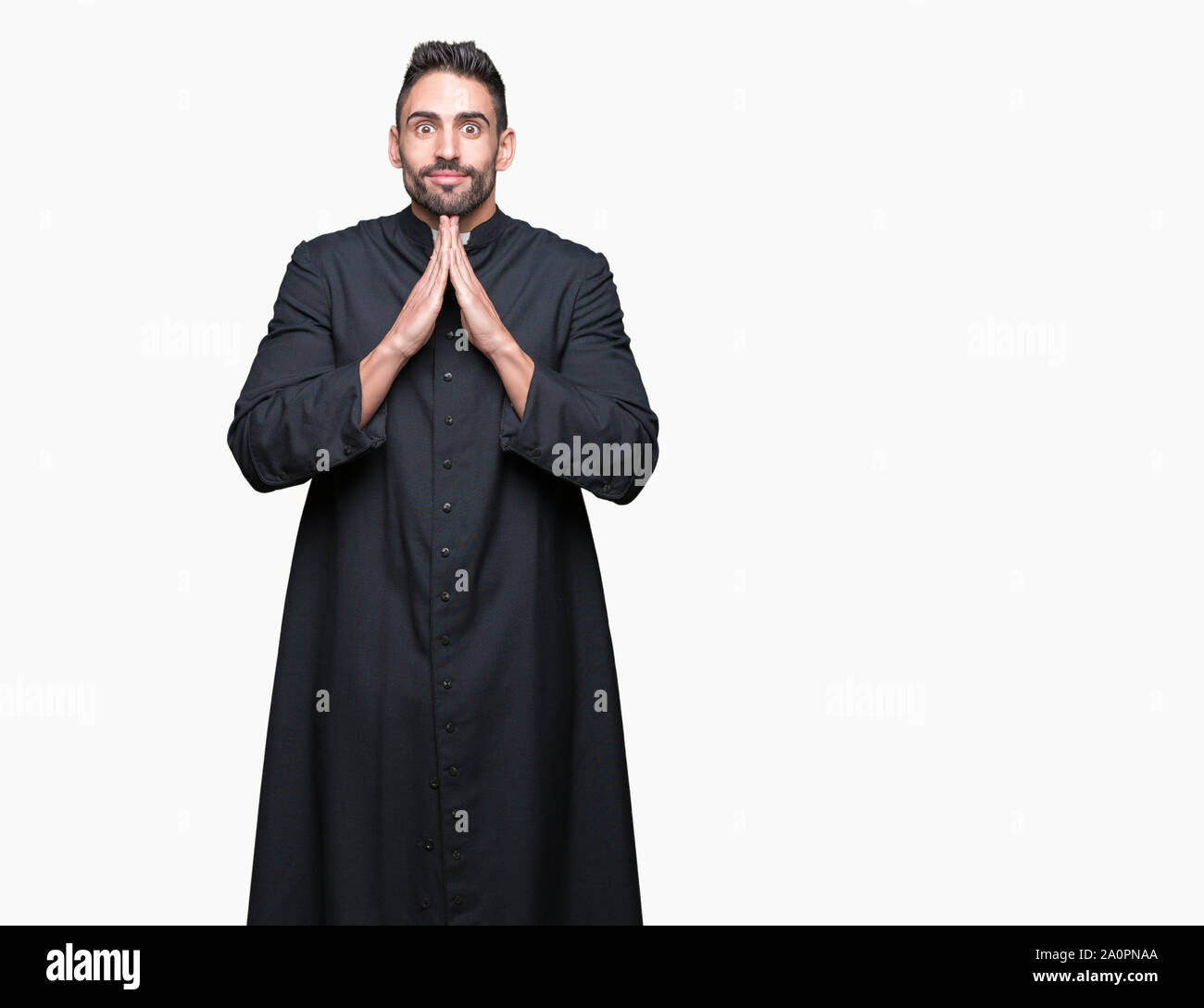 Young Christian priest over isolated background praying with hands ...