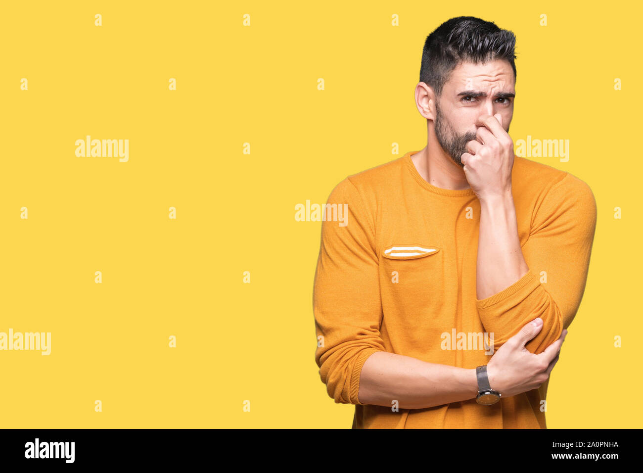 Young handsome man over isolated background smelling something stinky ...