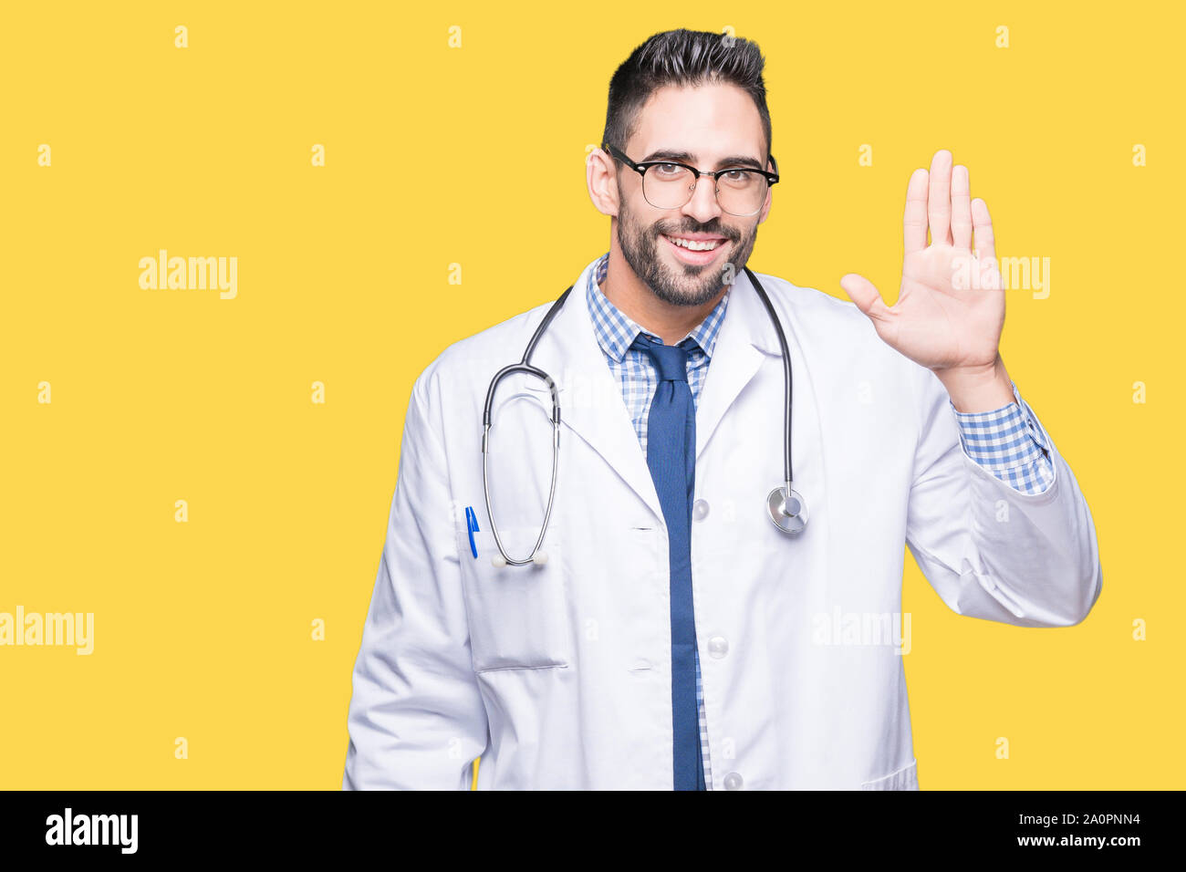 Handsome young doctor man over isolated background Waiving saying hello ...