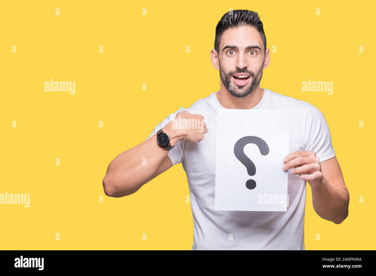 Handsome young man holding paper with question mark over isolated ...