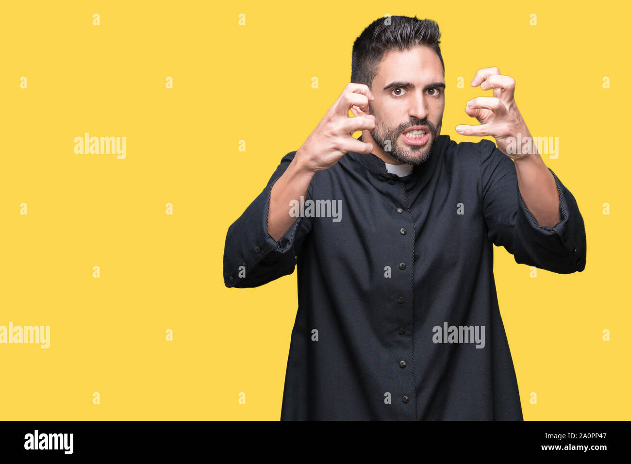Young Christian priest over isolated background Shouting frustrated ...