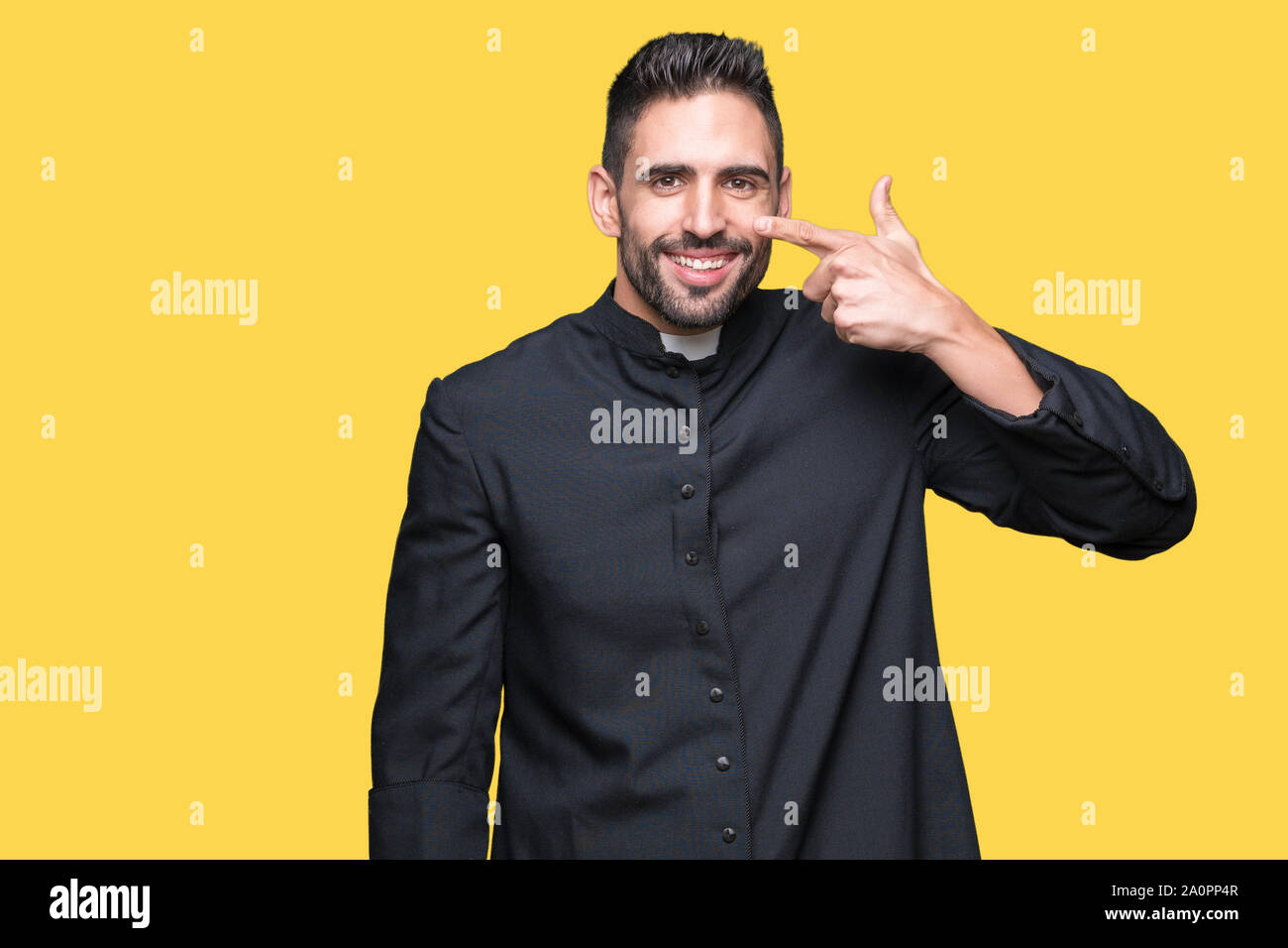 Young Christian priest over isolated background Pointing with hand ...