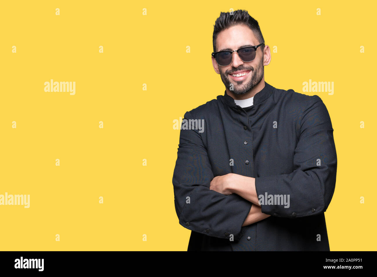 Young Christian priest wearing sunglasses over isolated background ...