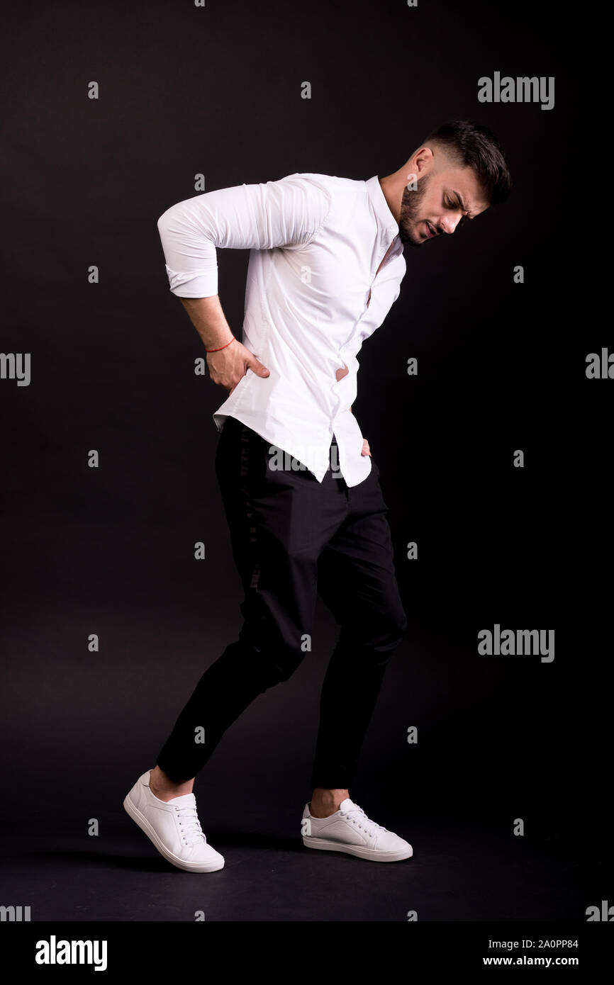 Back pain. Isolated handsome man on the black background suffer froma ...