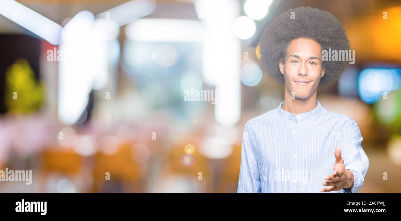 Young african american man with afro hair smiling friendly offering ...