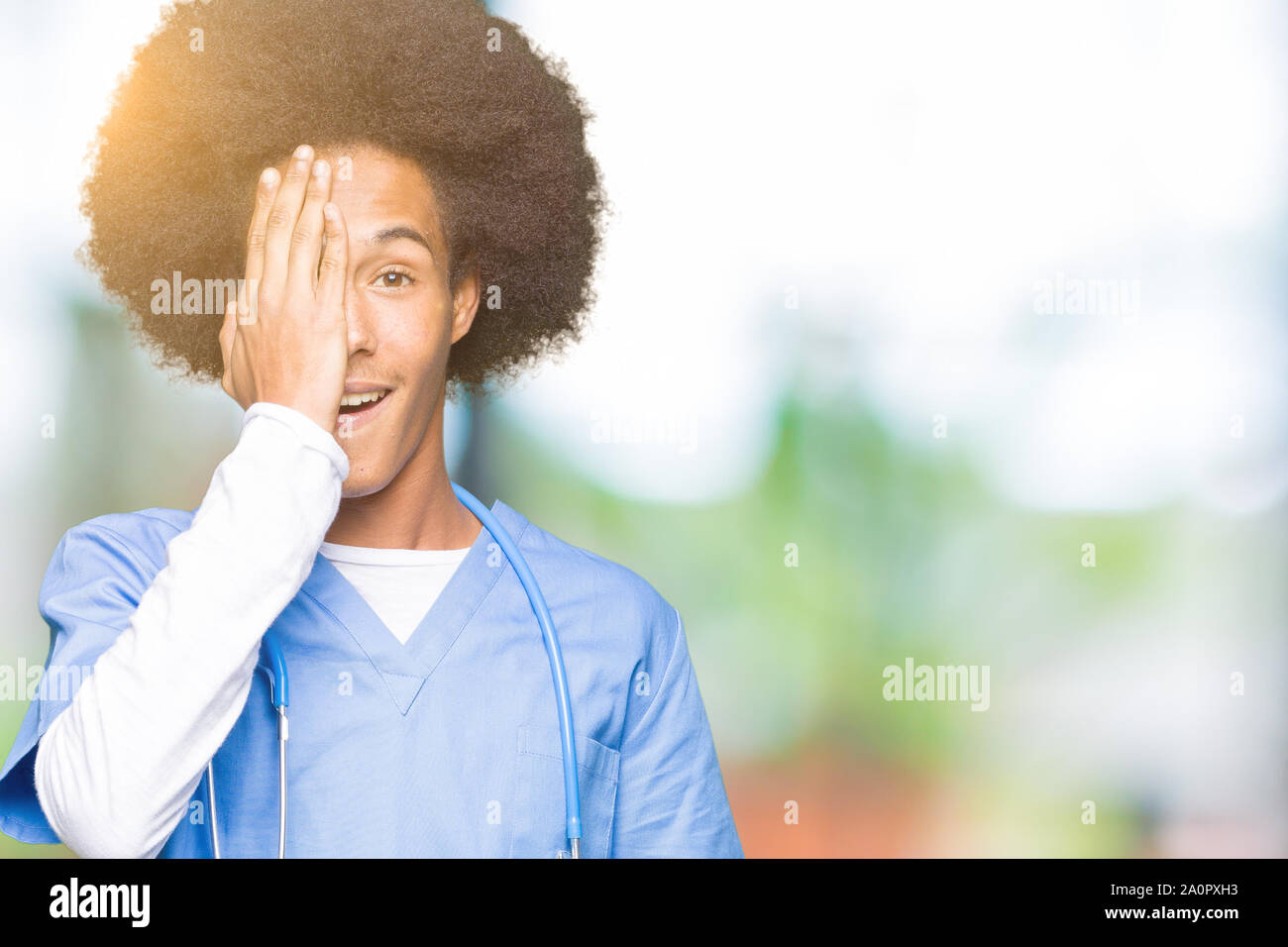 Young african american doctor man with afro hair covering one eye with ...