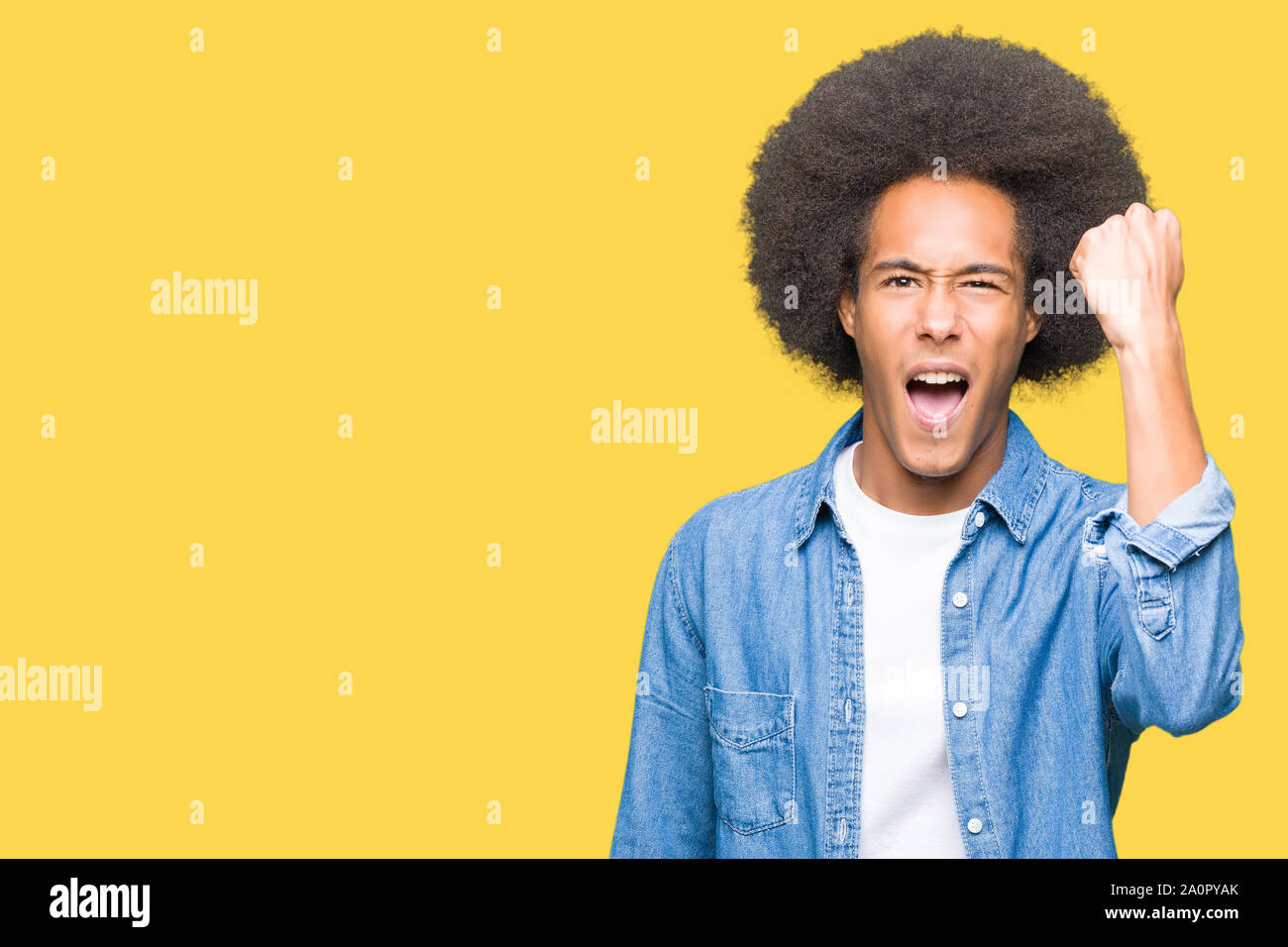 Young african american man with afro hair angry and mad raising fist ...