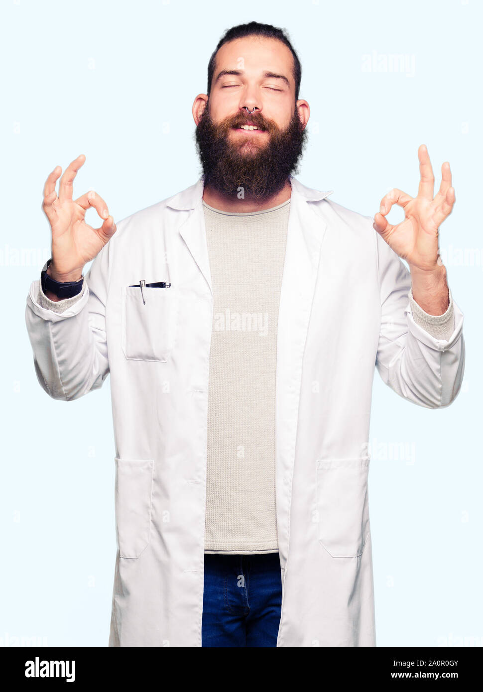 Young blond scientist man wearing white coat relax and smiling with ...