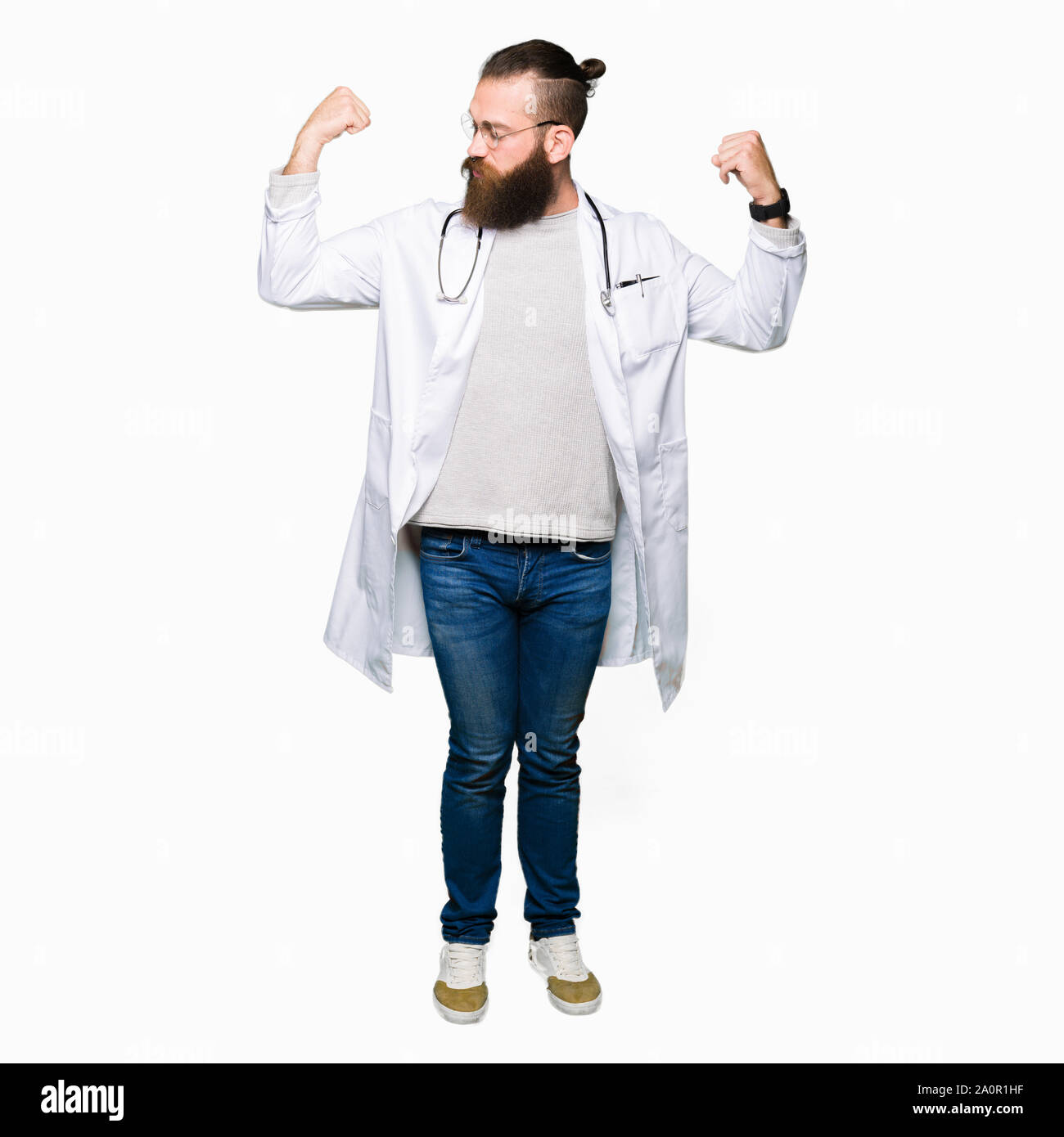 Young blond doctor man with beard wearing medical coat showing arms ...