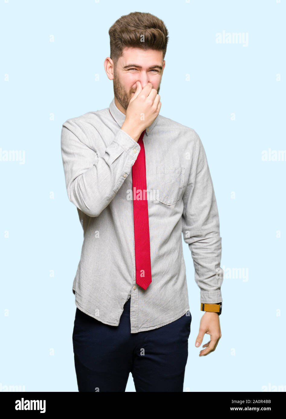 Young handsome business man smelling something stinky and disgusting ...