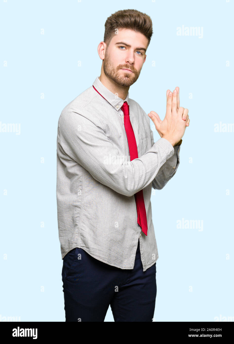 Young handsome business man Holding symbolic gun with hand gesture ...