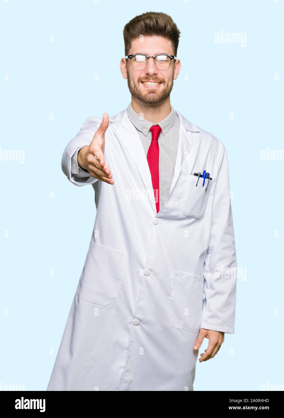 Young handsome scientist man wearing glasses smiling friendly offering ...