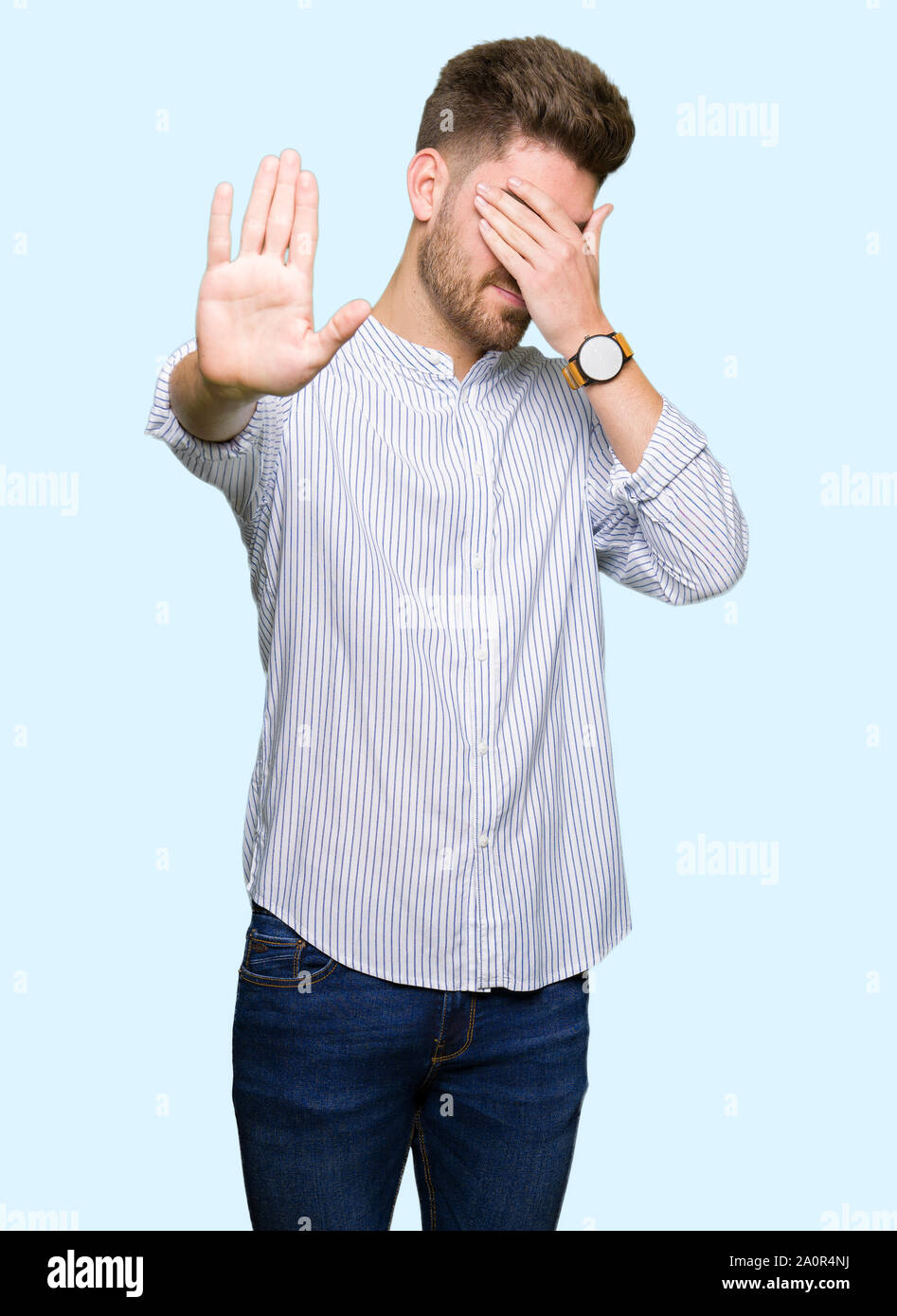 Young handsome man covering eyes with hands and doing stop gesture with ...
