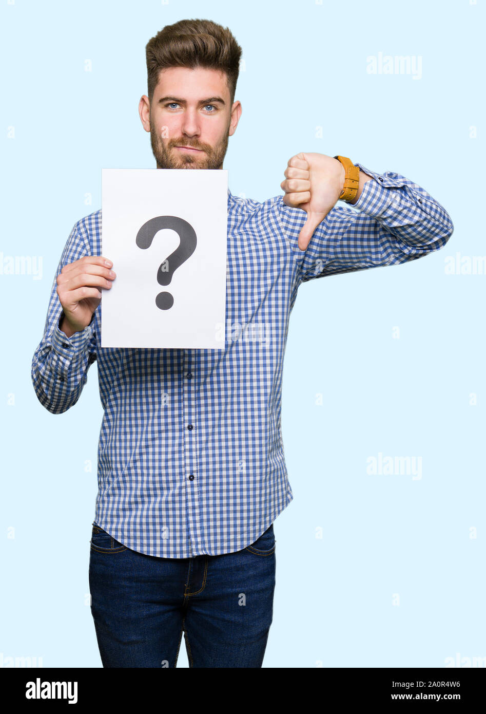 Young handsome man holding paper with question mark with angry face ...