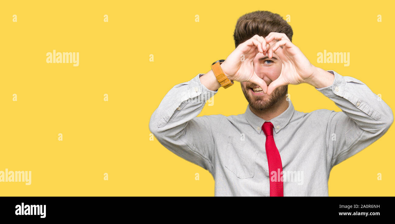 Young handsome business man Doing heart shape with hand and fingers ...