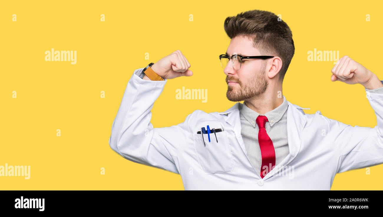 Young handsome scientist man wearing glasses showing arms muscles ...