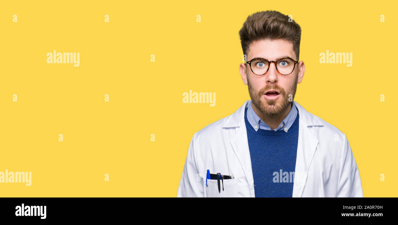 Young handsome scientist man wearing glasses afraid and shocked with ...