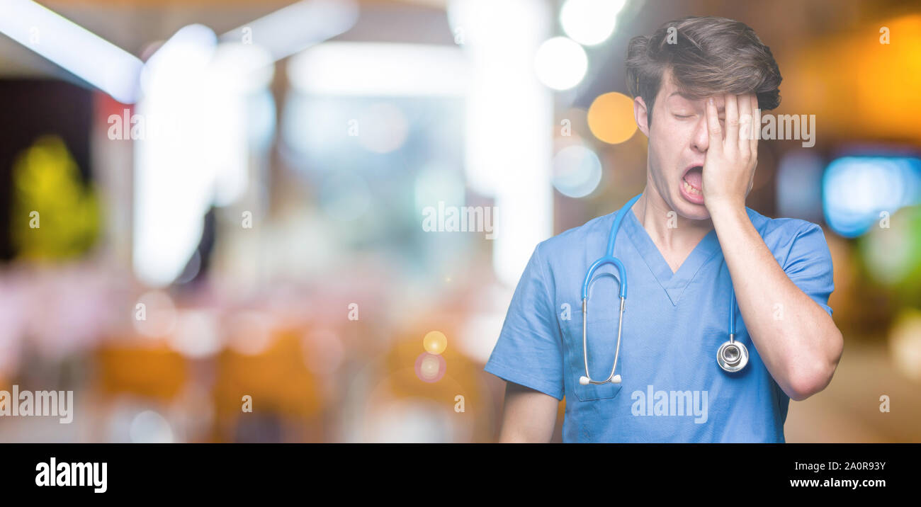 Young doctor wearing medical uniform over isolated background Yawning ...