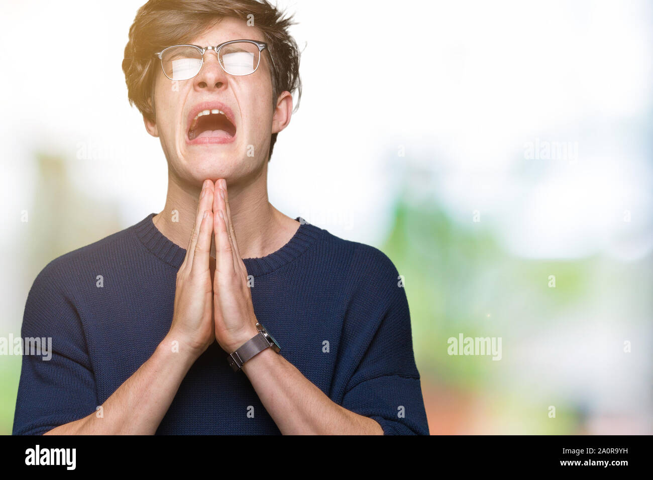 Young handsome man wearing glasses over isolated background begging and ...