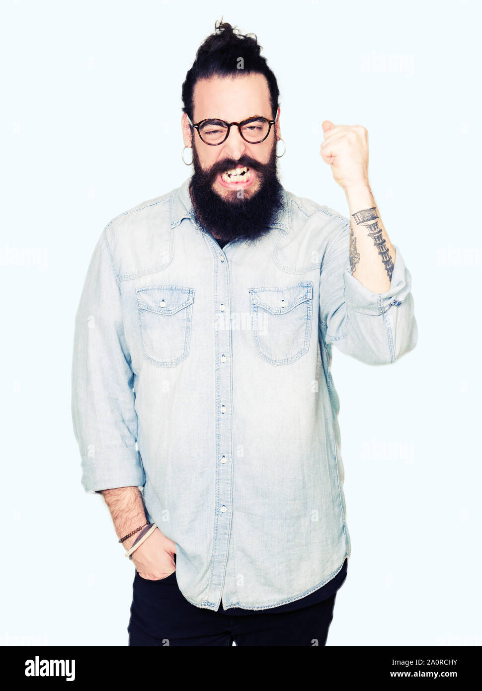 Young hipster man with long hair and beard wearing glasses angry and ...