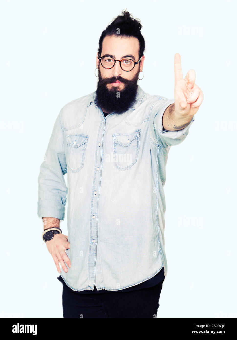 Young hipster man with long hair and beard wearing glasses Pointing ...