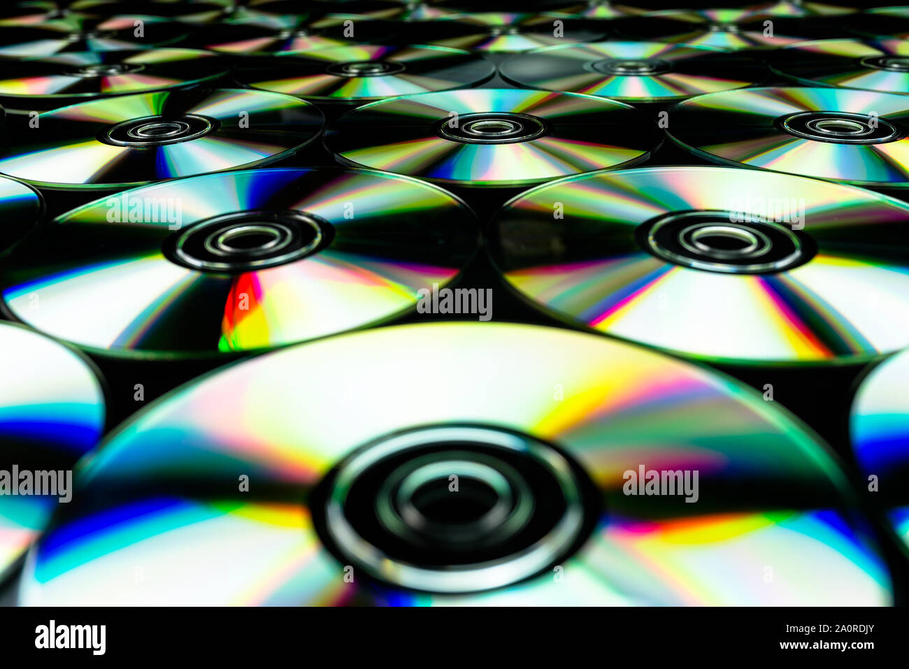CDs / DVDs lying on a black background with colorful reflections of ...