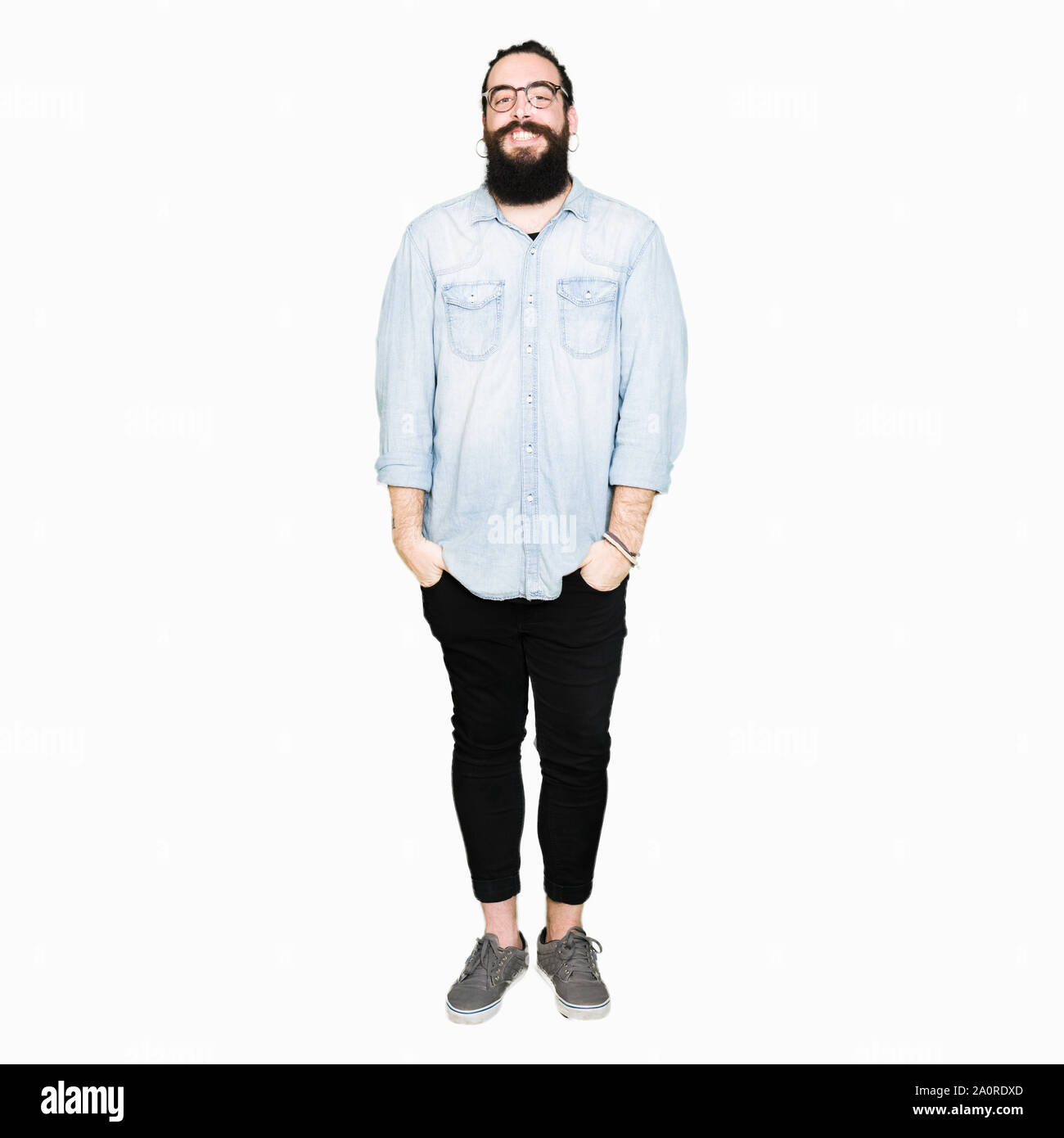 Young hipster man with long hair and beard wearing glasses looking away ...