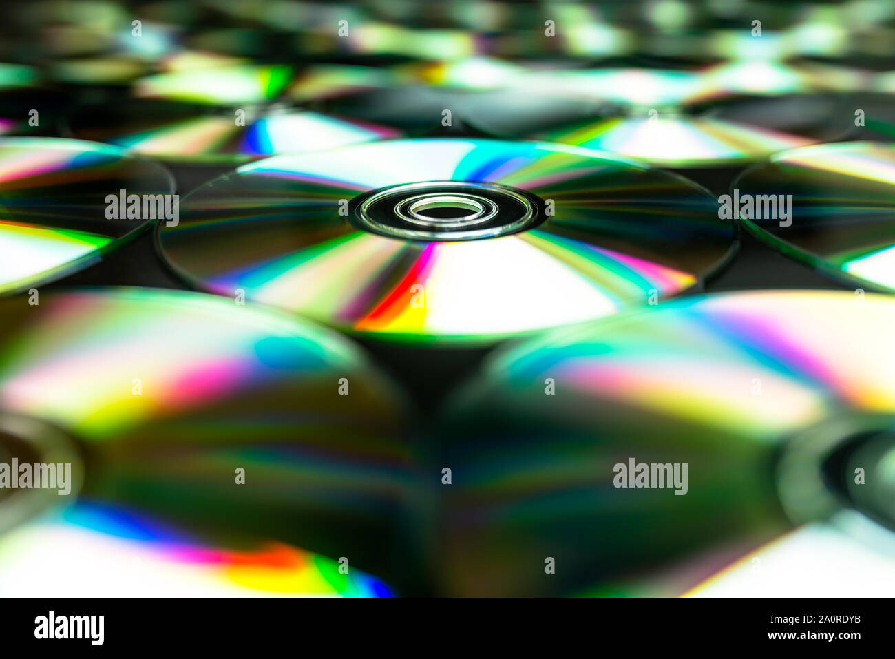 CDs / DVDs lying on a black background with colorful reflections of ...
