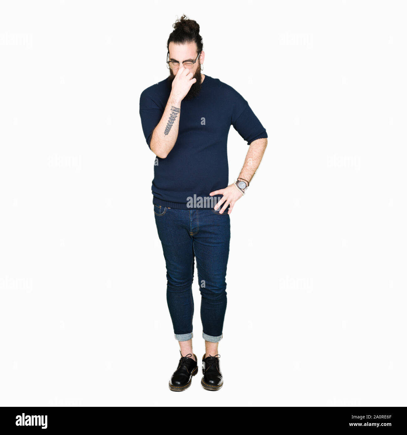 Young hipster man with long hair and beard wearing glasses smelling ...