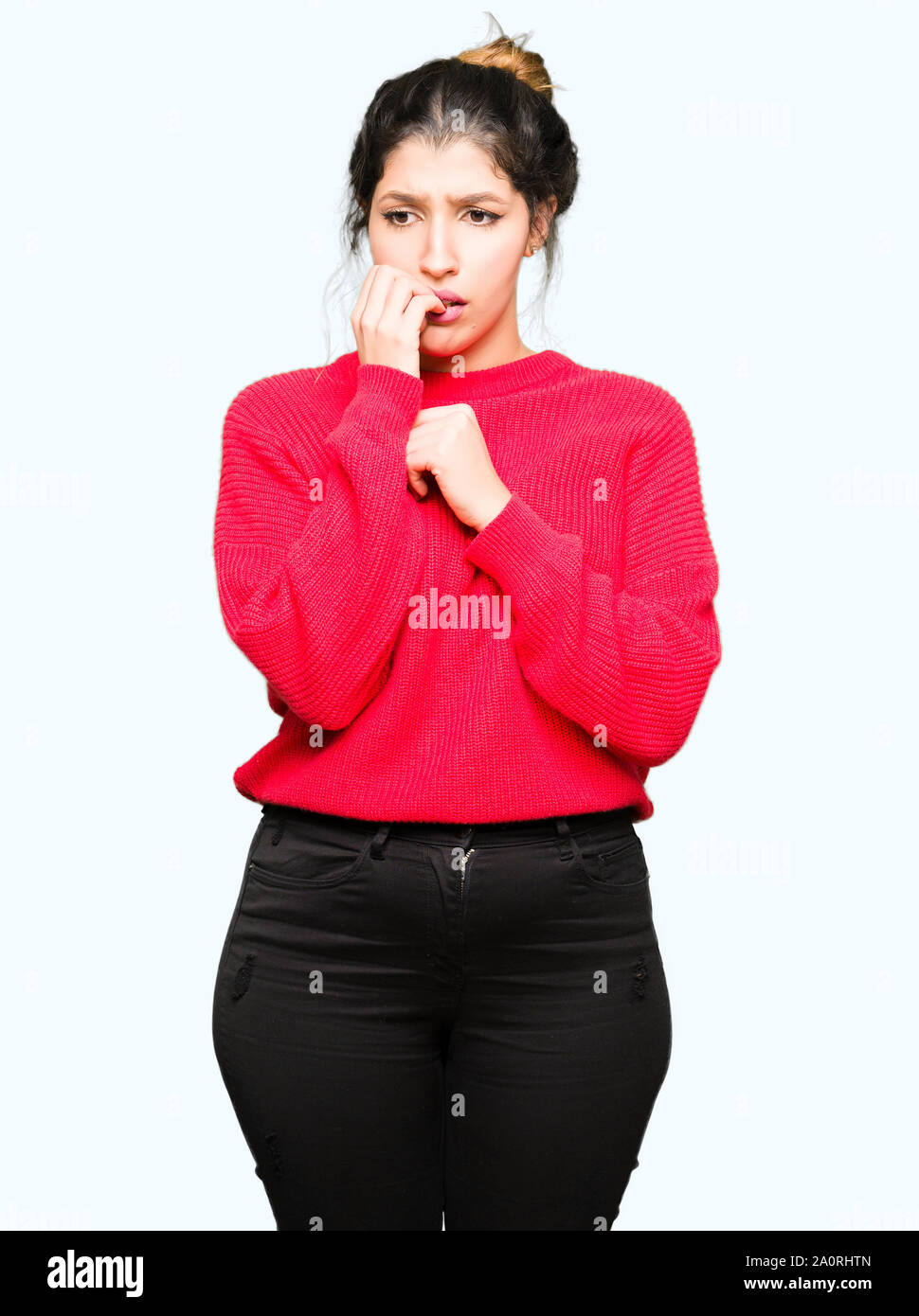 Young beautiful woman wearing red sweater and bun looking stressed and ...