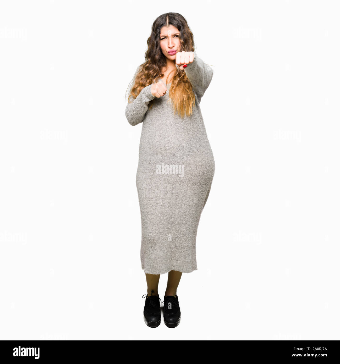 Young beautiful woman wearing winter dress Punching fist to fight ...