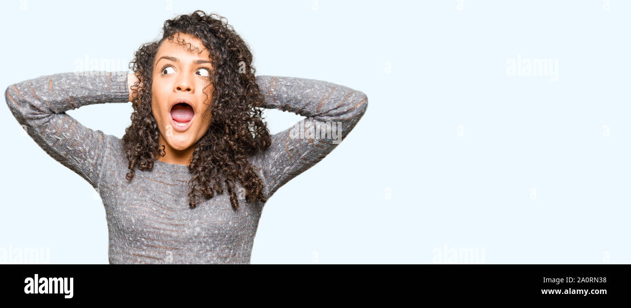 Young beautiful woman with curly hair wearing grey sweater Crazy and ...