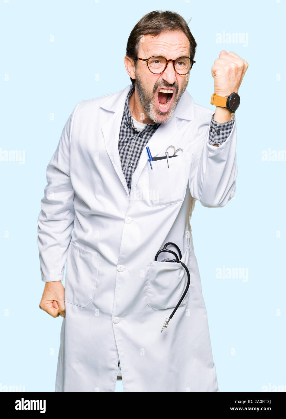 Middle age doctor men wearing medical coat angry and mad raising fist ...