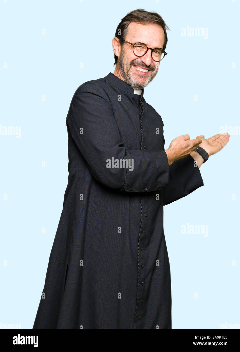 Middle age priest man wearing catholic robe Inviting to enter smiling ...