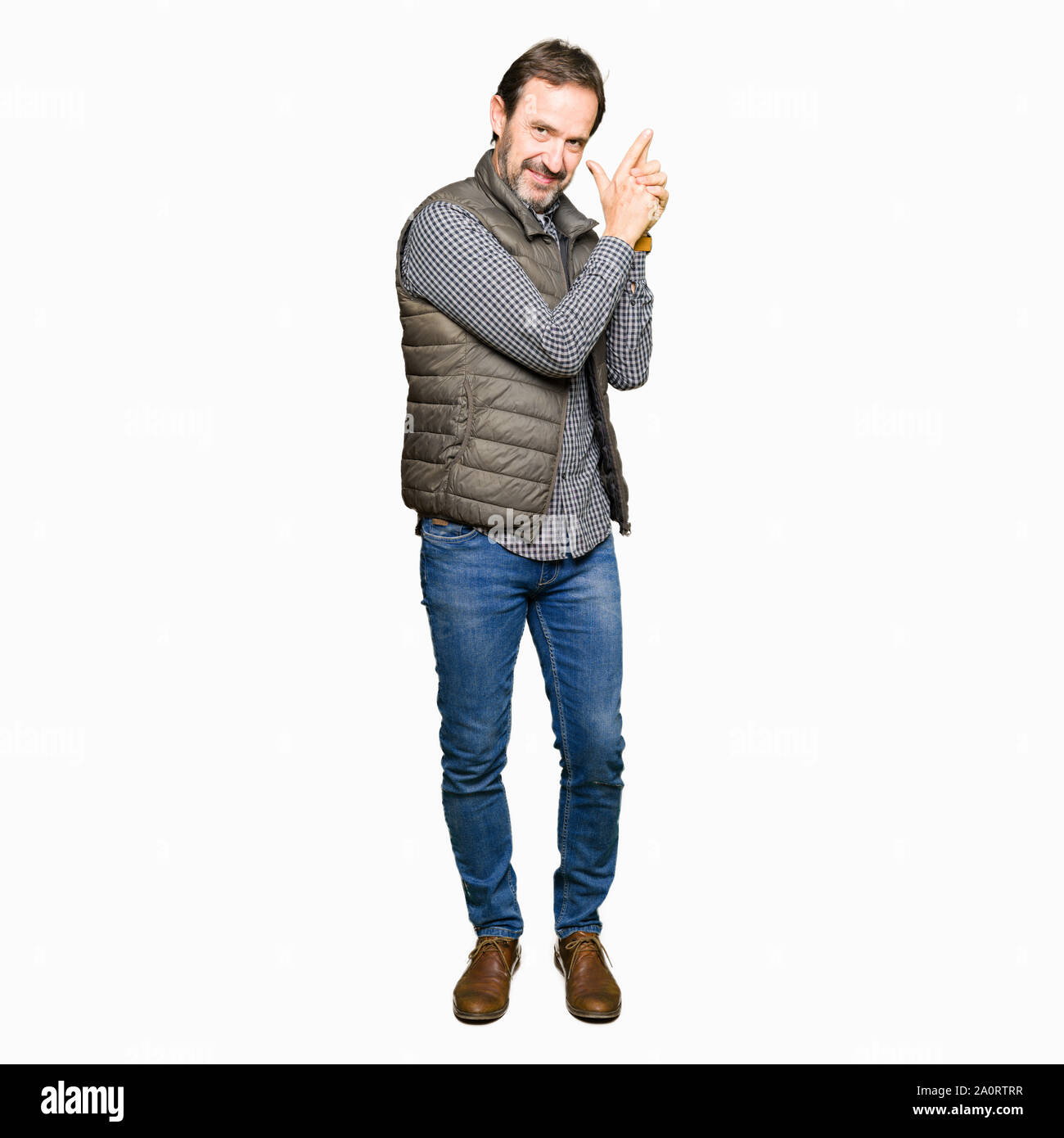 Middle age handsome man wearing winter vest Holding symbolic gun with ...