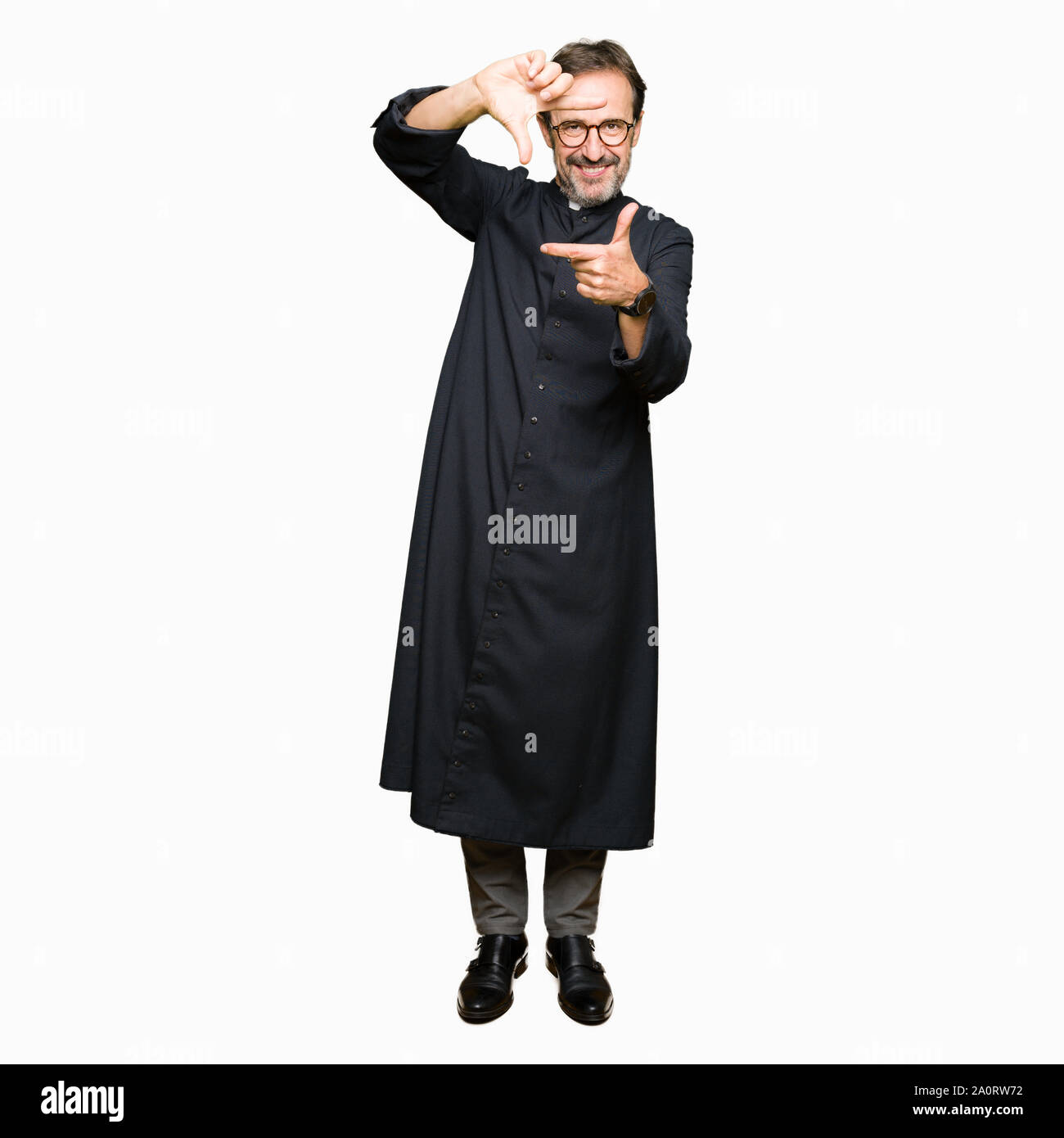Middle age priest man wearing catholic robe smiling making frame with ...