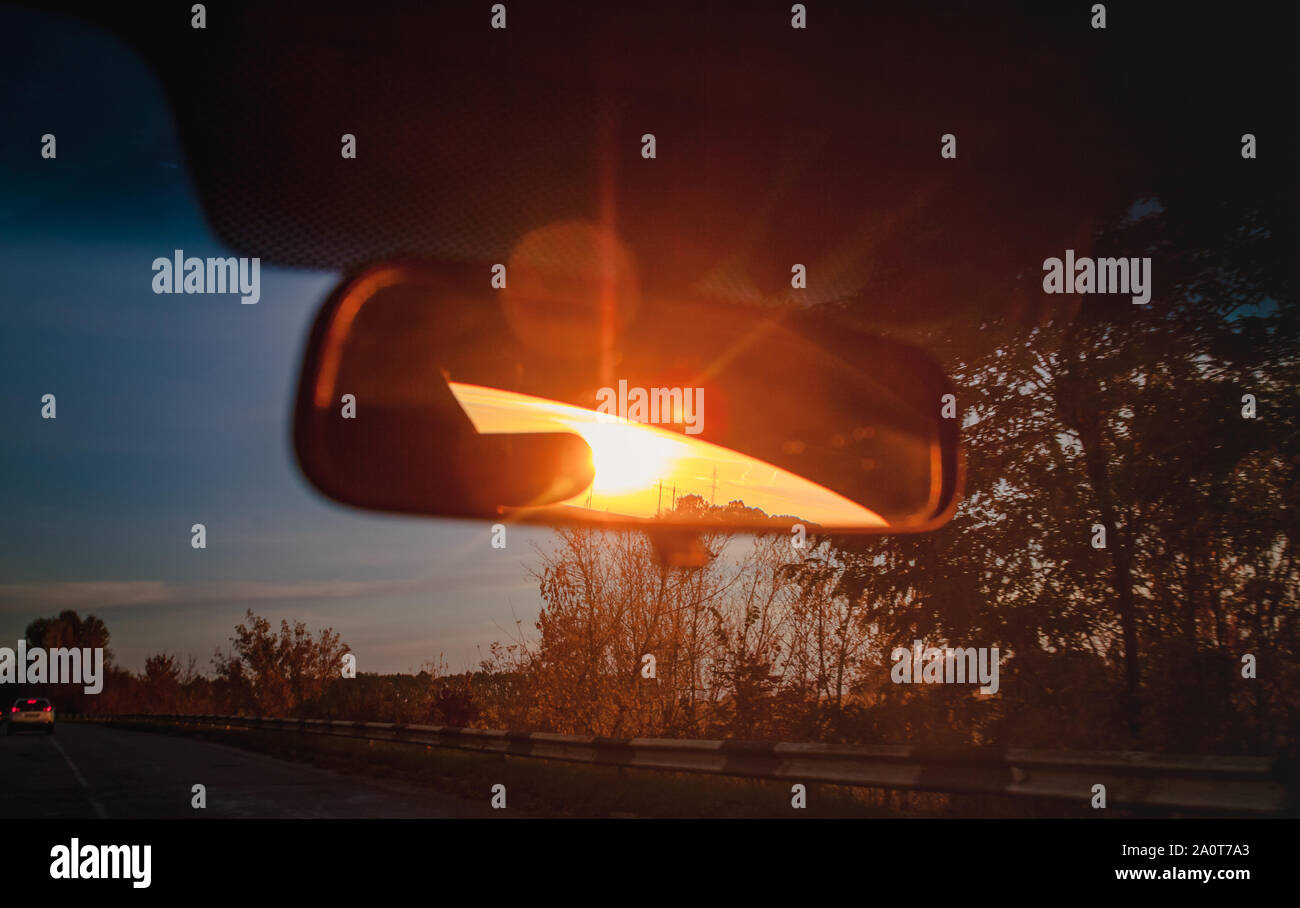 sunset red sunbeams in a salon inside rearview mirror of a car. Close ...