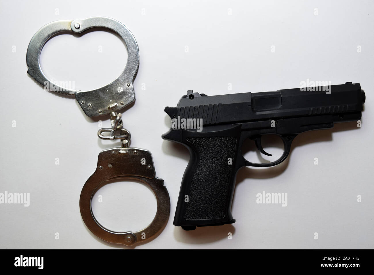 Black gun and handcuffs isolated on white background Stock Photo - Alamy