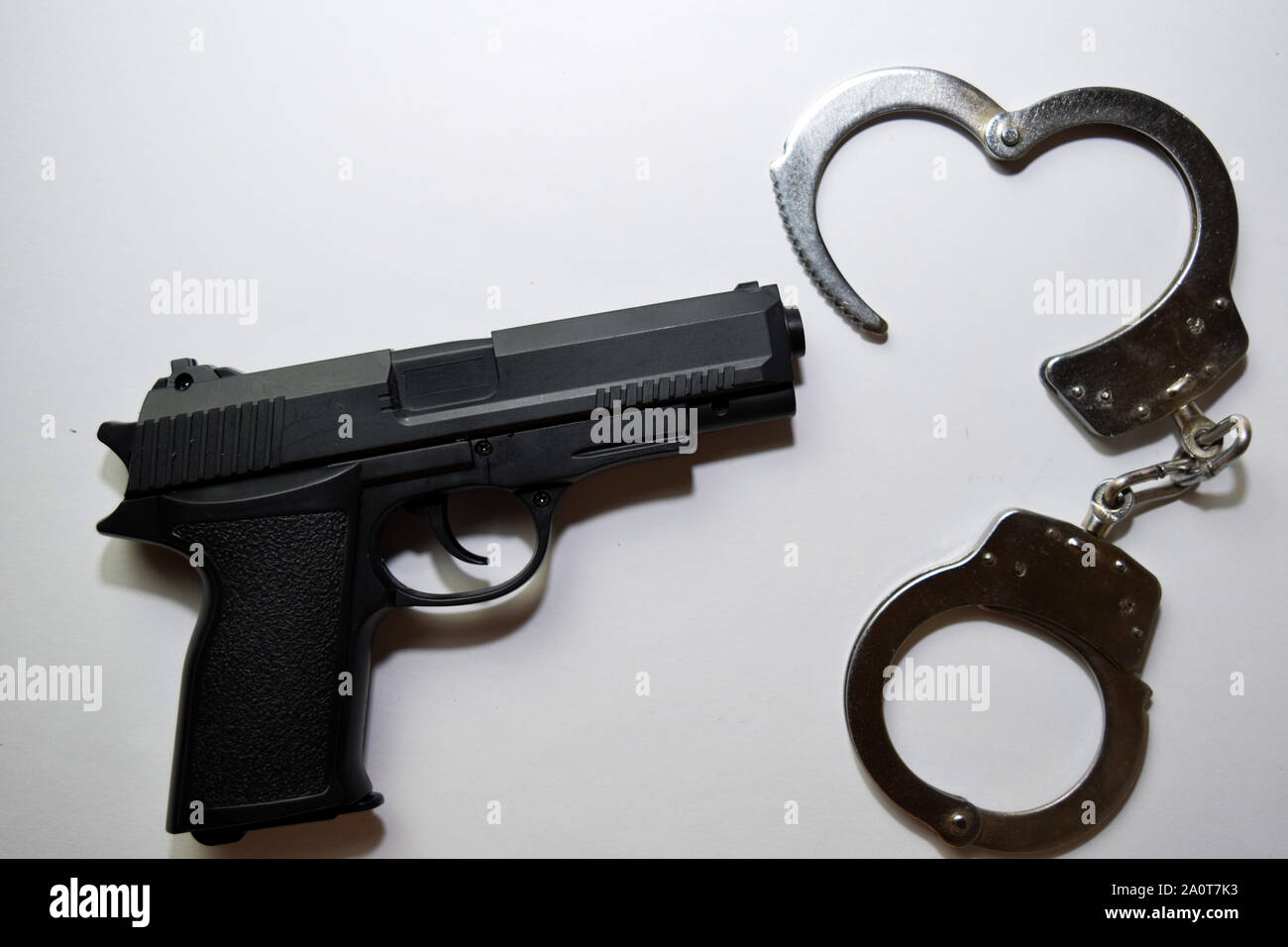 Black gun and handcuffs isolated on white background Stock Photo - Alamy