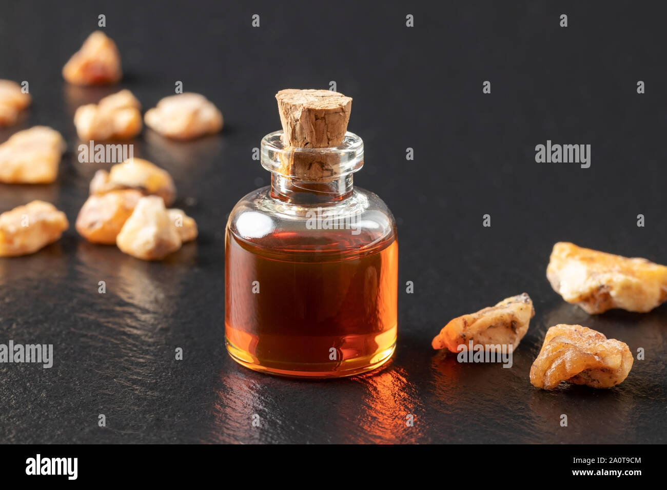 A bottle of styrax essential oil on a black background with benzoin ...