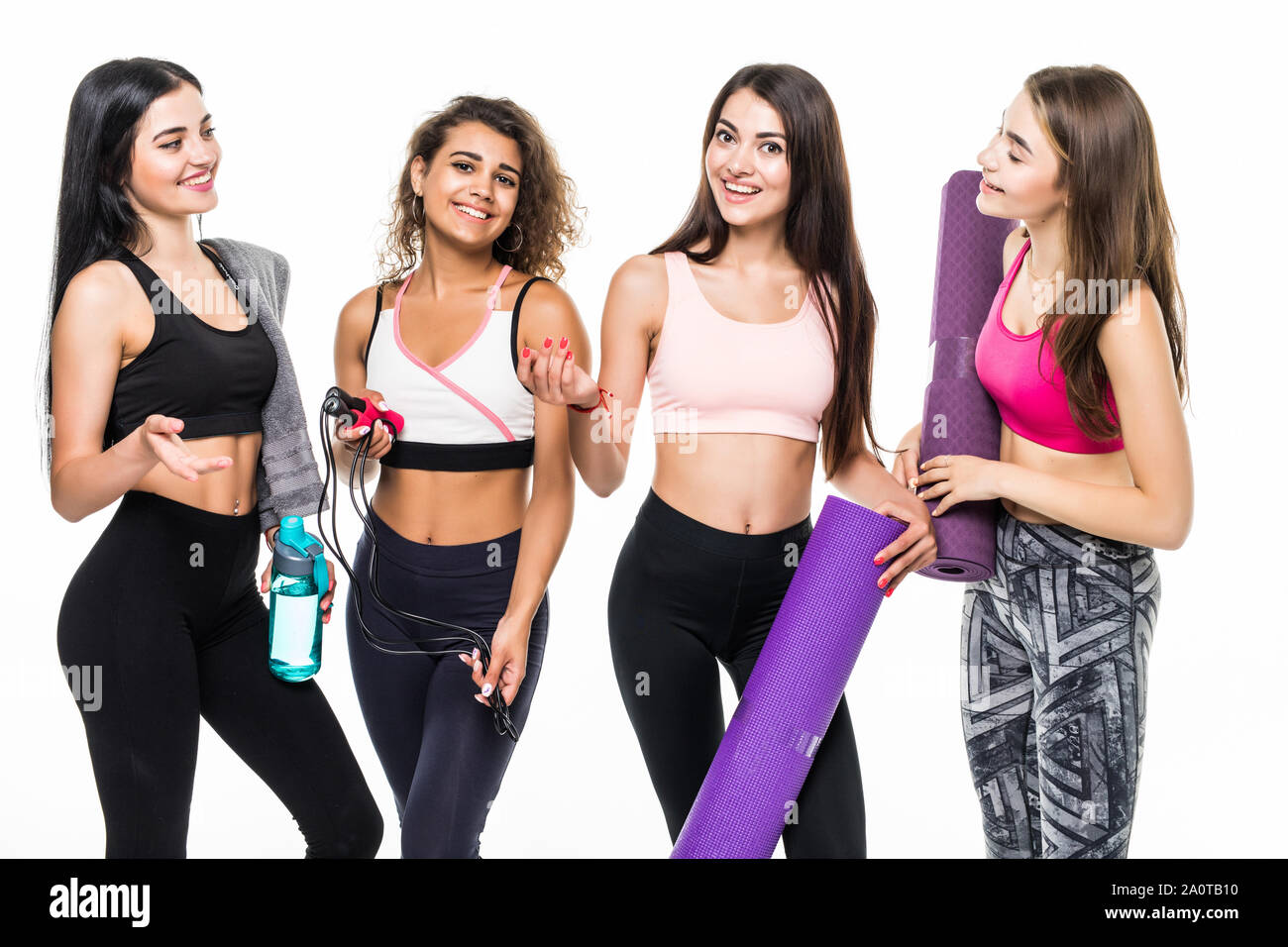 Four fitness girls in sportwear holding exercises equipment on white ...